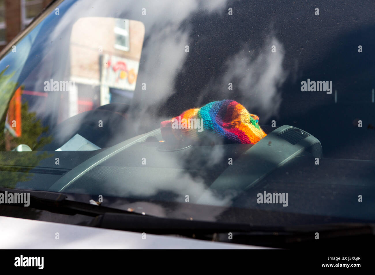Looking through the windscreen of a van at a rainbow coloured wolly hat ...