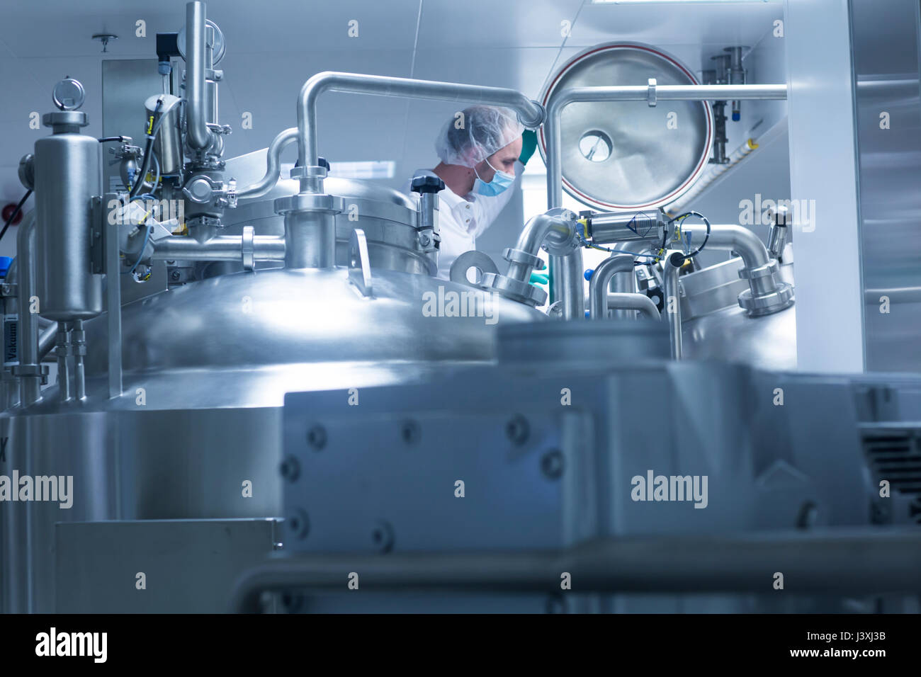 Worker operating pharmaceutical production equipment in pharmaceutical ...