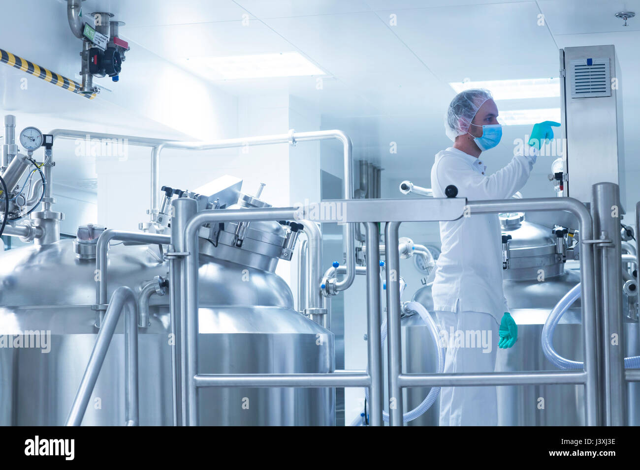 Worker operating pharmaceutical production equipment in pharmaceutical ...