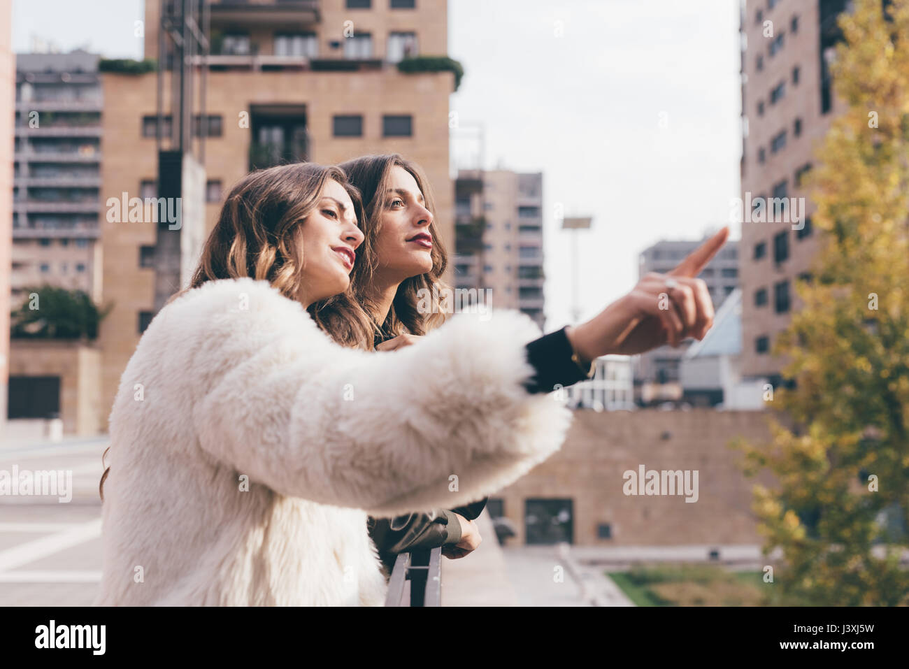 Twin sisters on roof of building, looking at city, Milan, Italy Stock ...