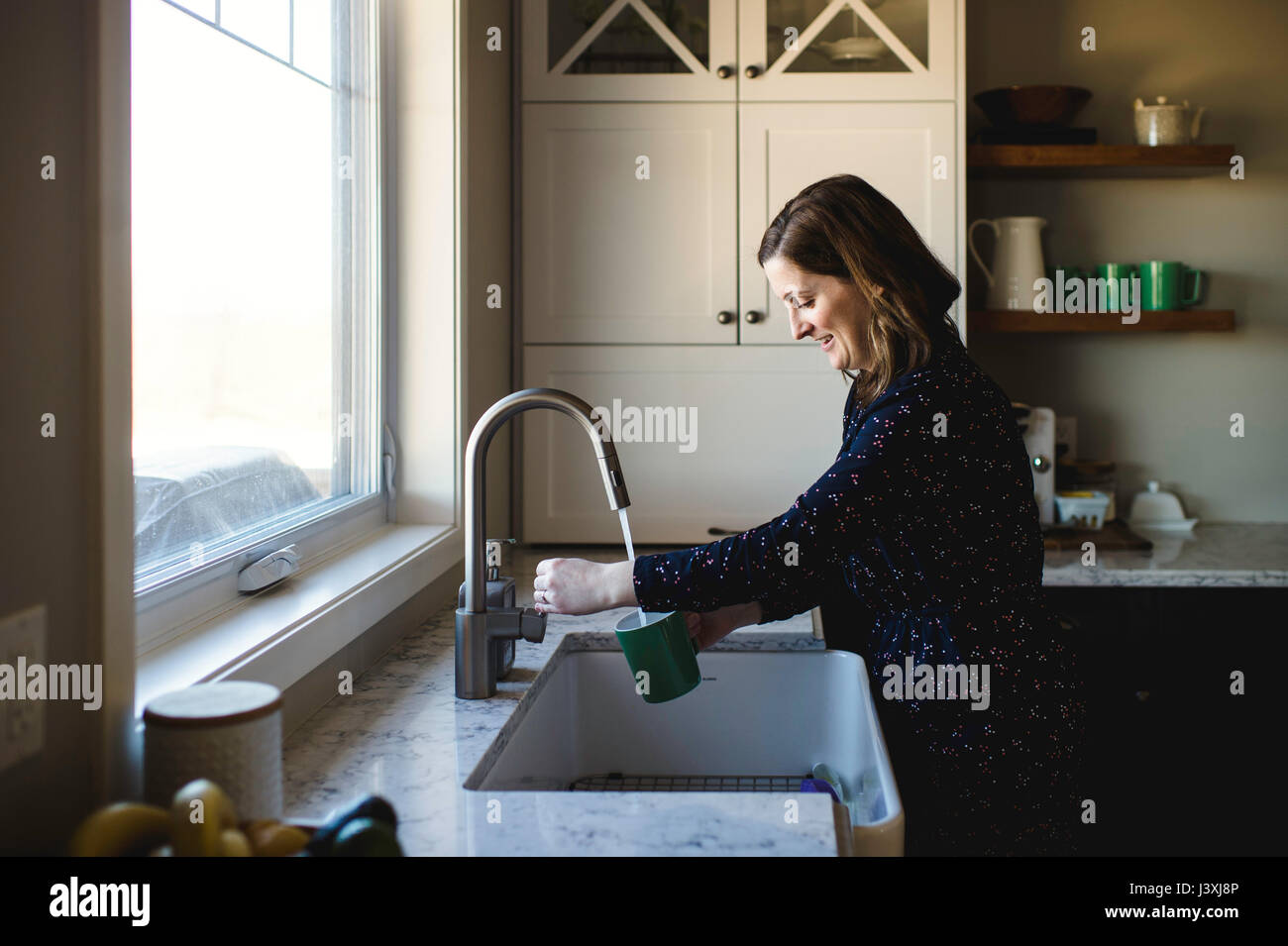 Woman filling up cup at kitchen sink Stock Photo - Alamy
