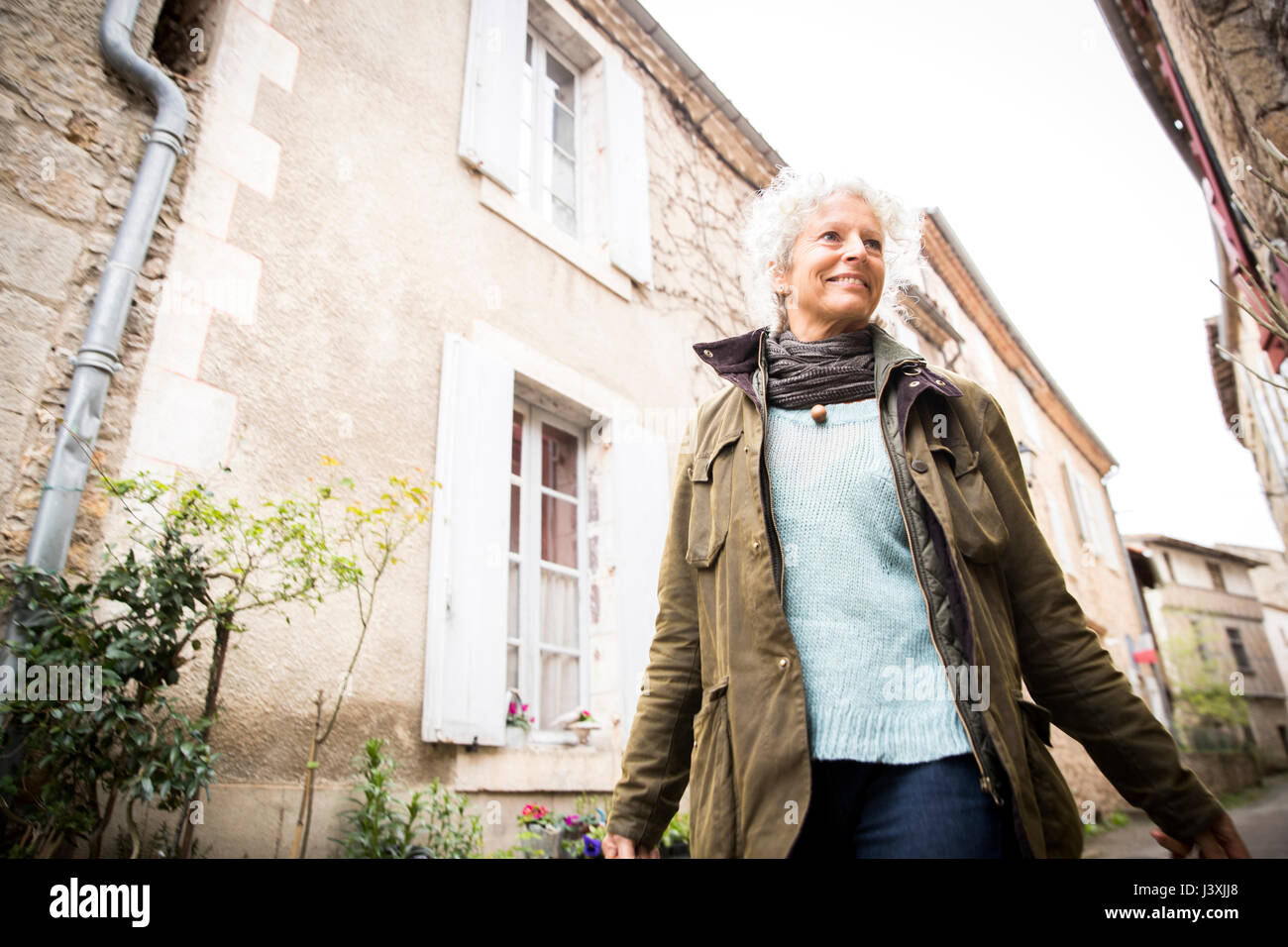 Woman walking in rural street smiling Stock Photo - Alamy