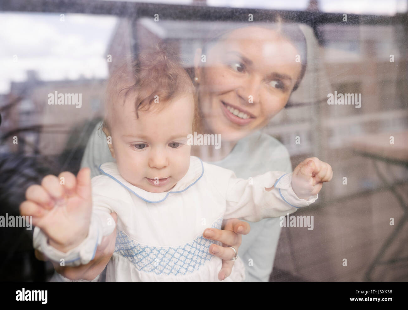 Mother and baby looking through glass window Stock Photo - Alamy