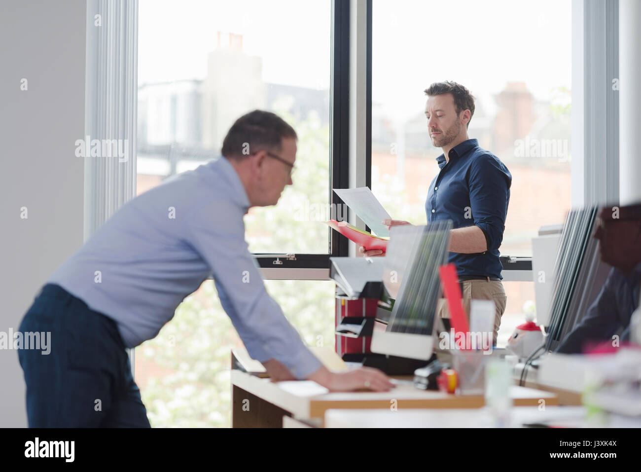 Male colleagues in discussion at office desk Stock Photo - Alamy