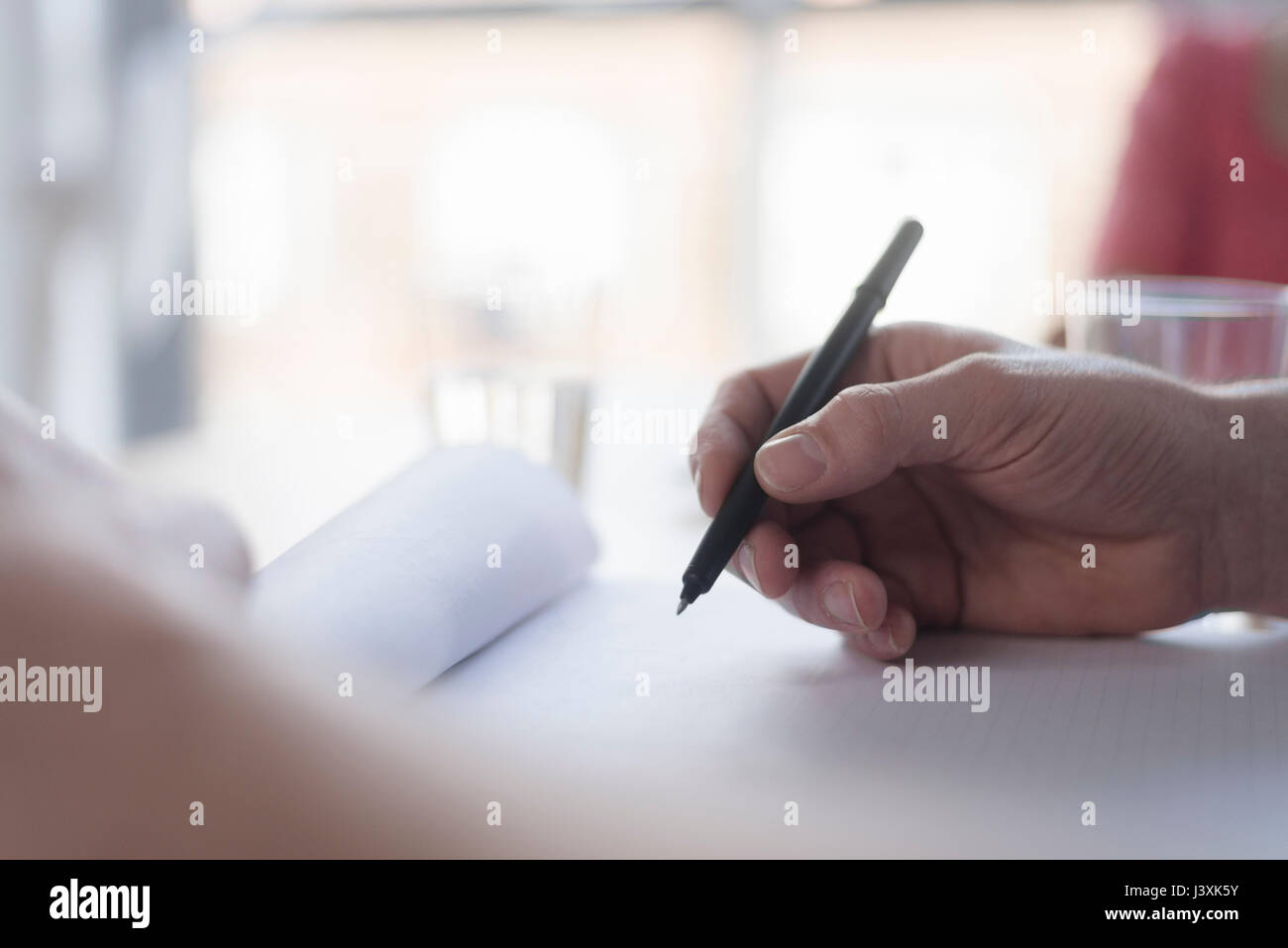 Man writing notes on desk, close up of hand Stock Photo - Alamy