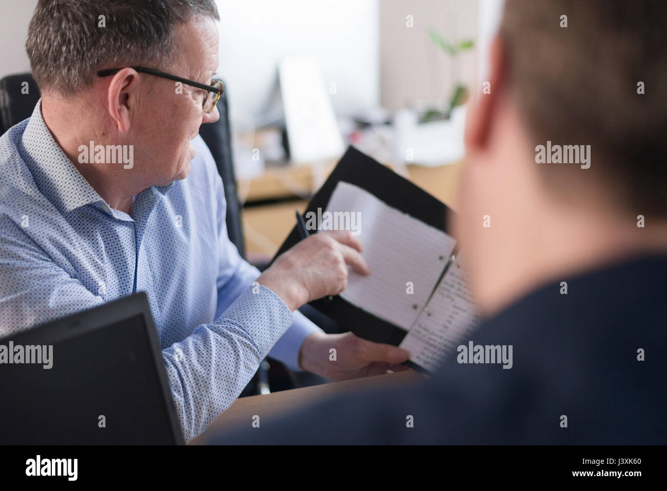 Male colleagues in discussion at office desk Stock Photo - Alamy
