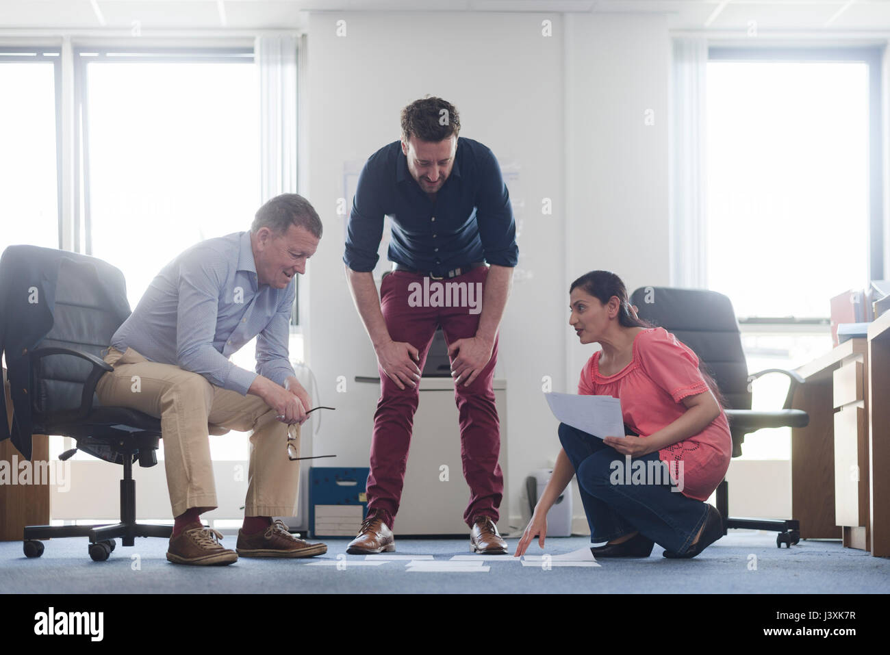 Colleagues discussing papers on office floor Stock Photo - Alamy