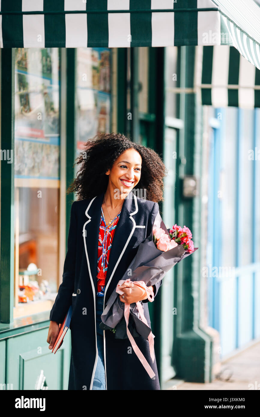Stylish woman strolling along street with bunch of flowers Stock Photo ...