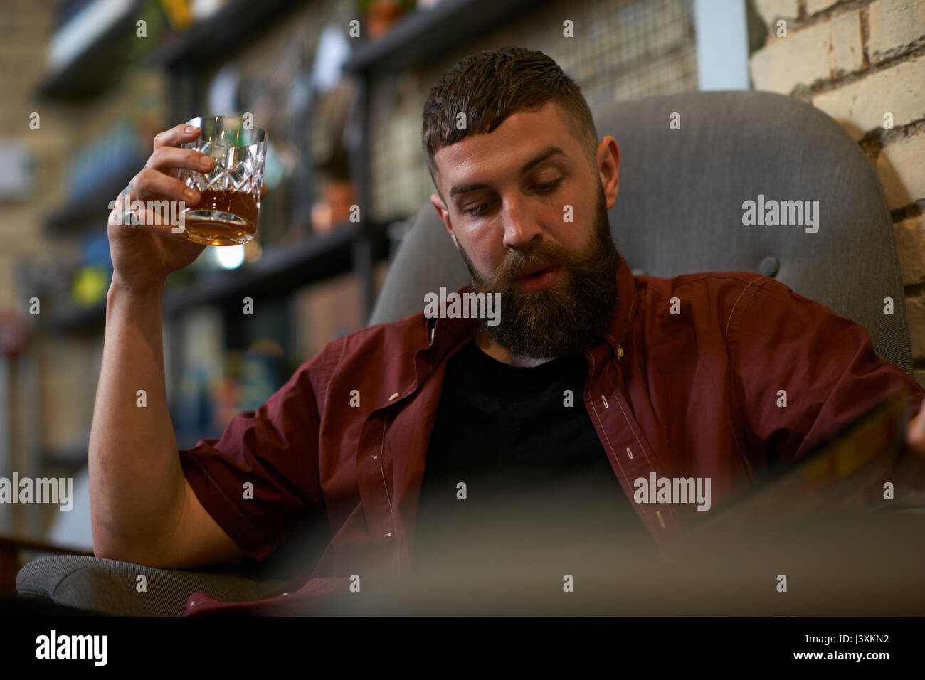 Young man with tumbler of spirit looking at menu in public house Stock ...