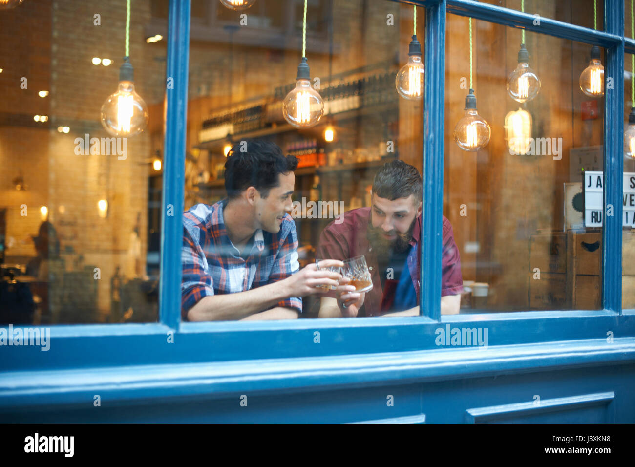 Window view of two men raising a glass in public house Stock Photo - Alamy