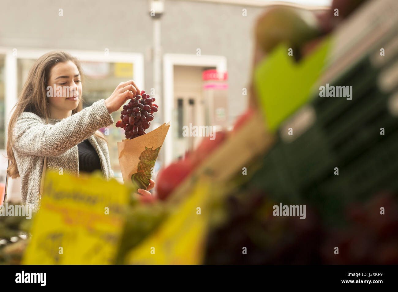 Young woman buying bunch of grapes from market stall Stock Photo - Alamy