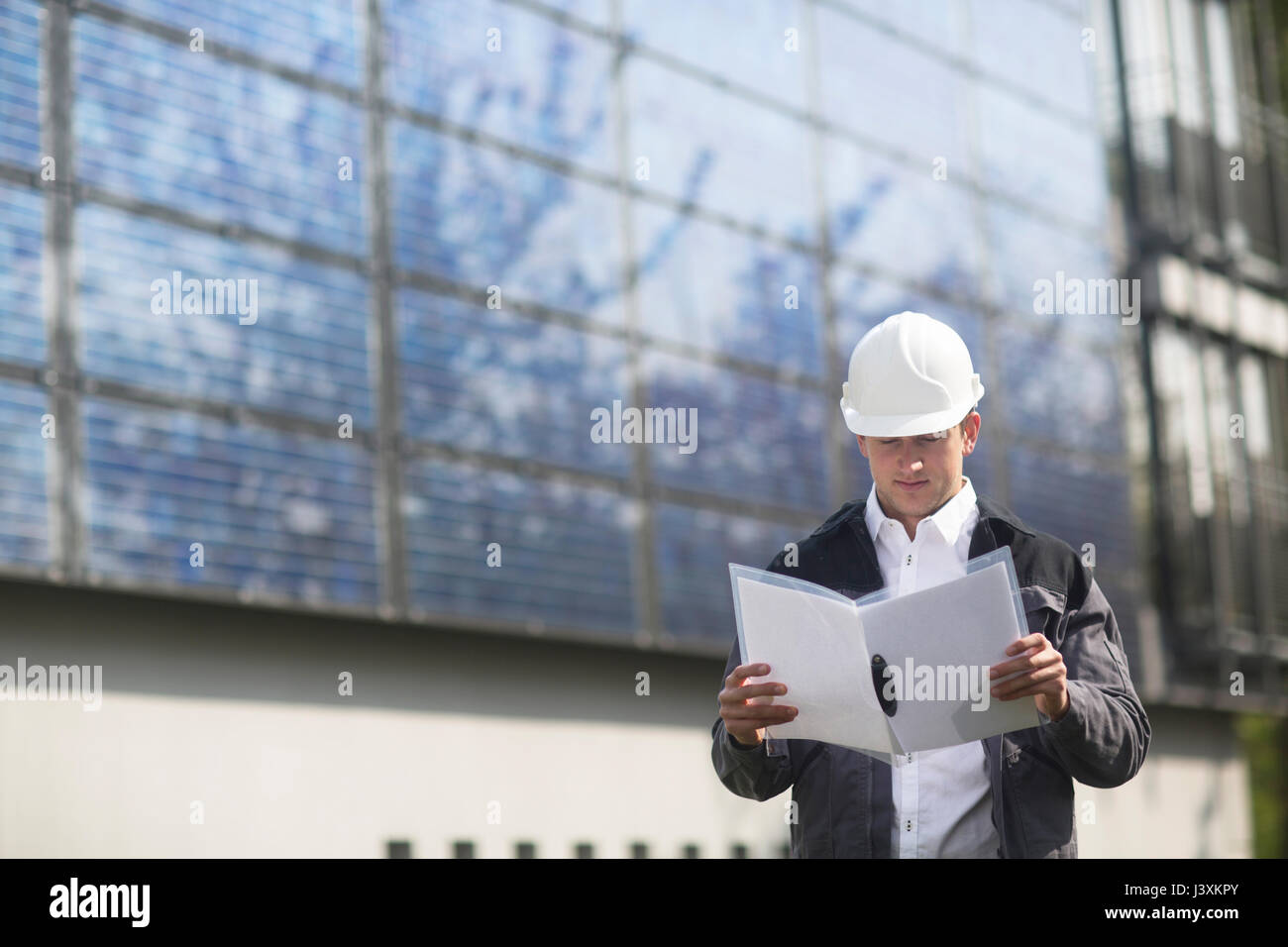 Male engineer looking at paperwork on solar panel site Stock Photo - Alamy