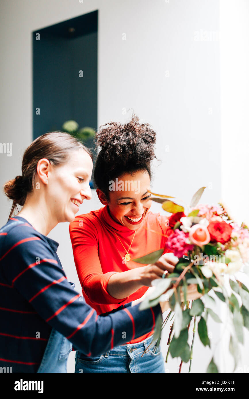 Florist and student arranging bouquet at flower arranging workshop ...
