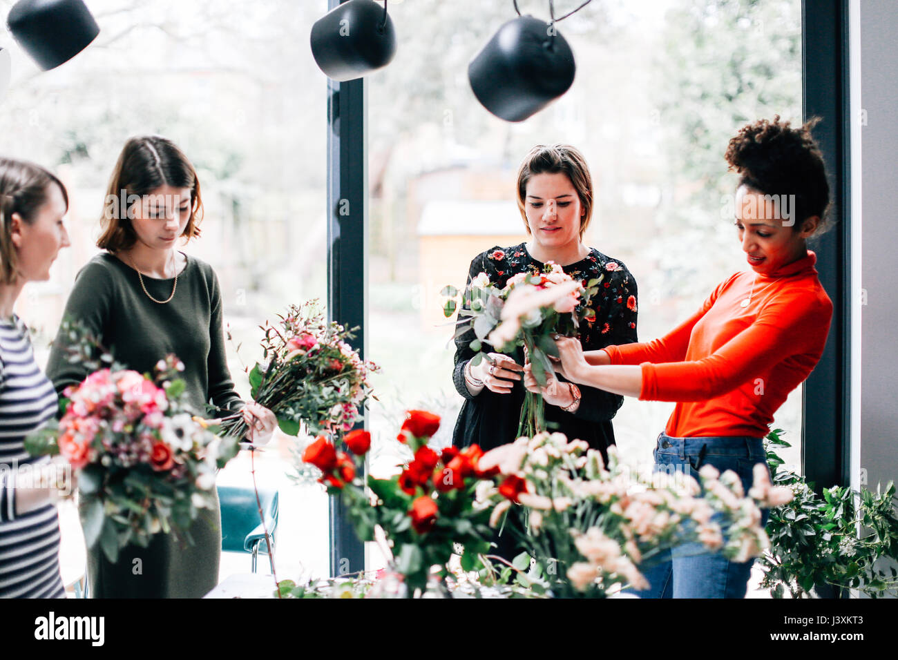 Florist and students arranging bouquets at flower arranging workshop ...