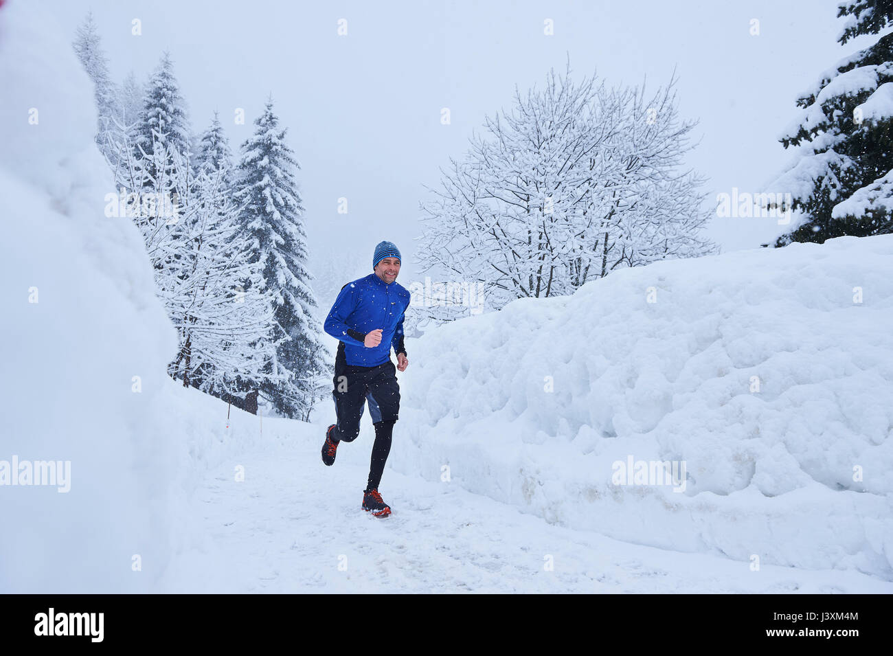 Male runner running on track in deep snow, Gstaad, Switzerland Stock ...
