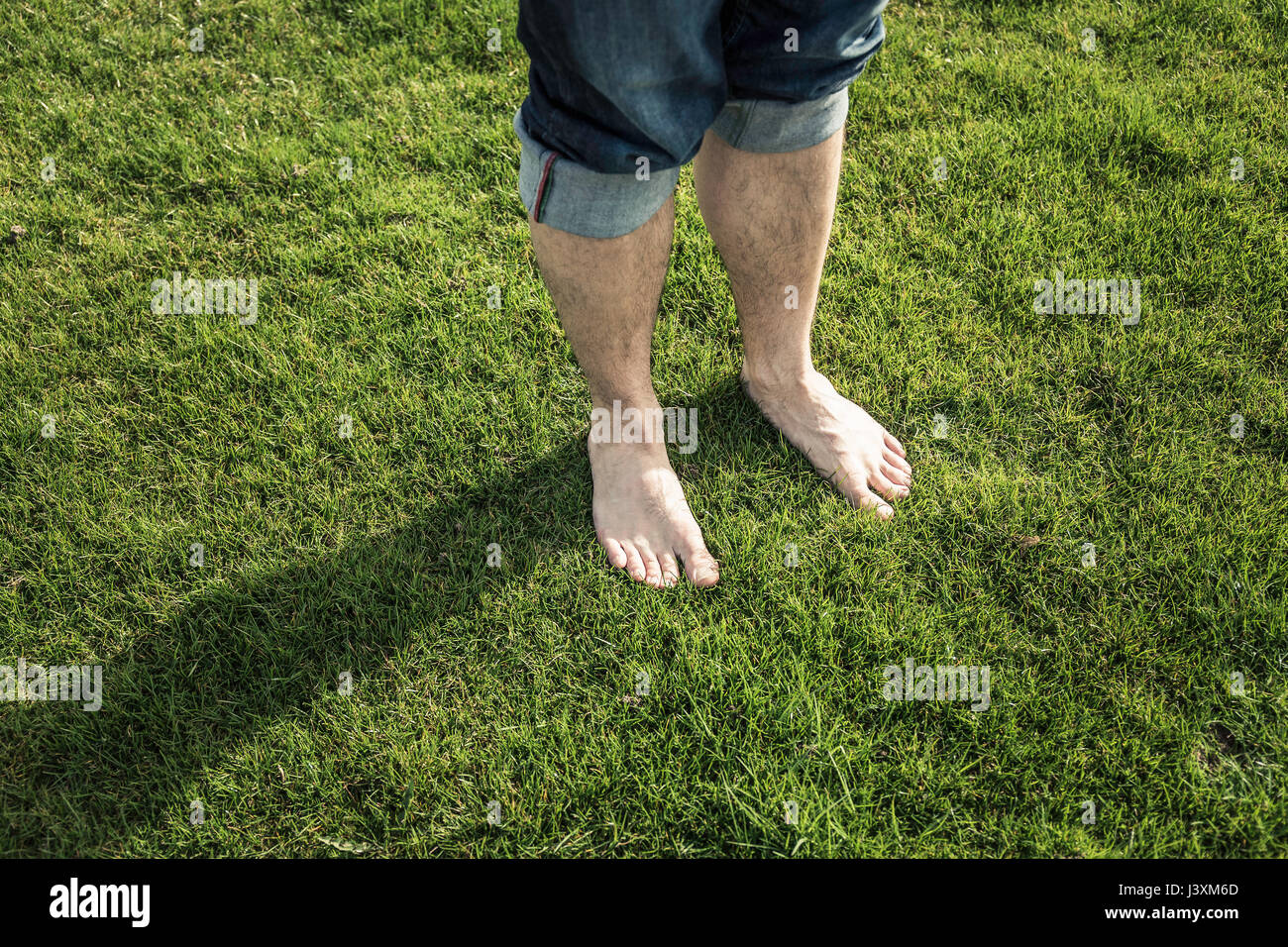 Legs and bare feet of man standing on green grass Stock Photo - Alamy