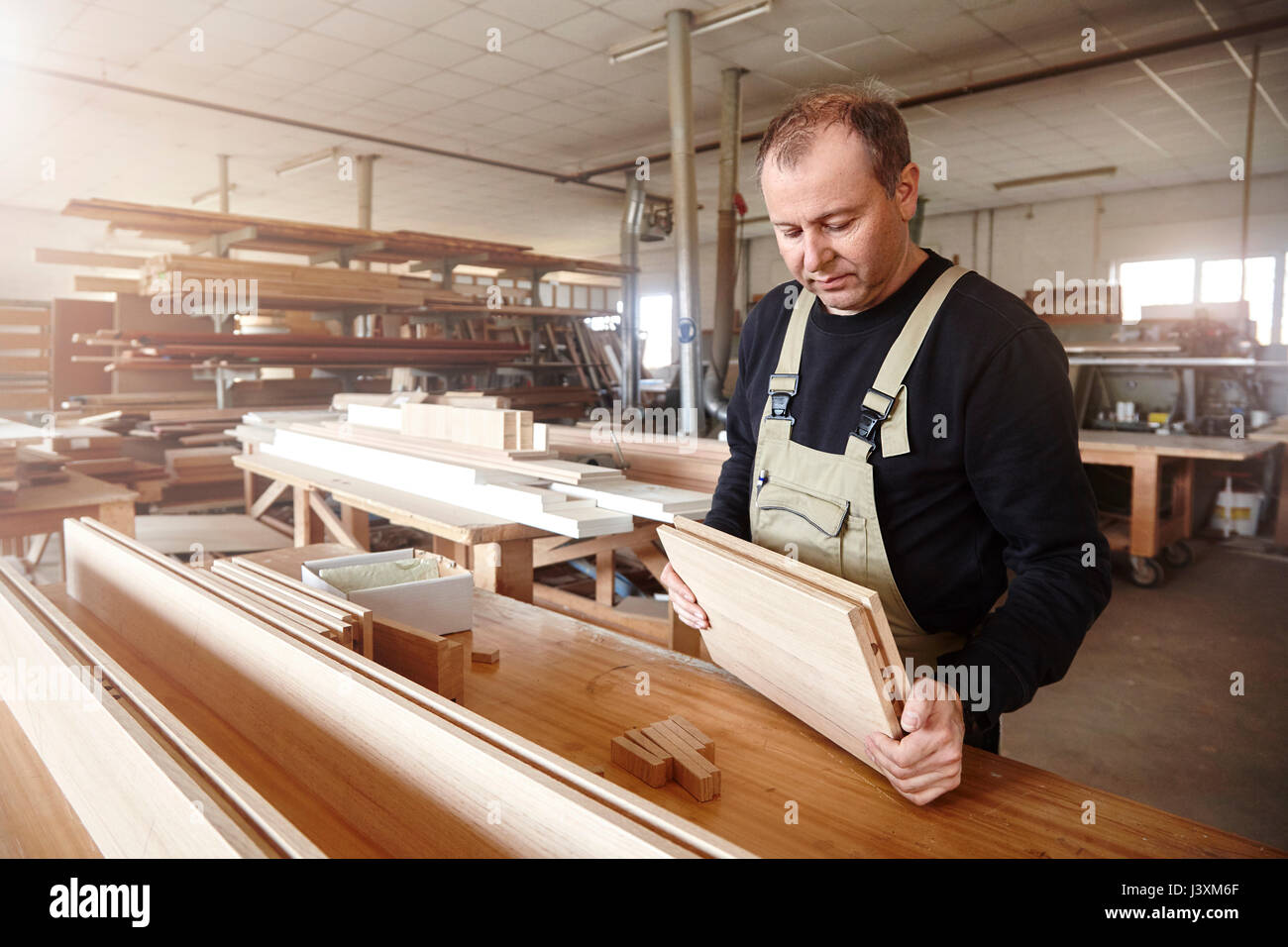 Male carpenter inspecting wood plank at workbench Stock Photo - Alamy