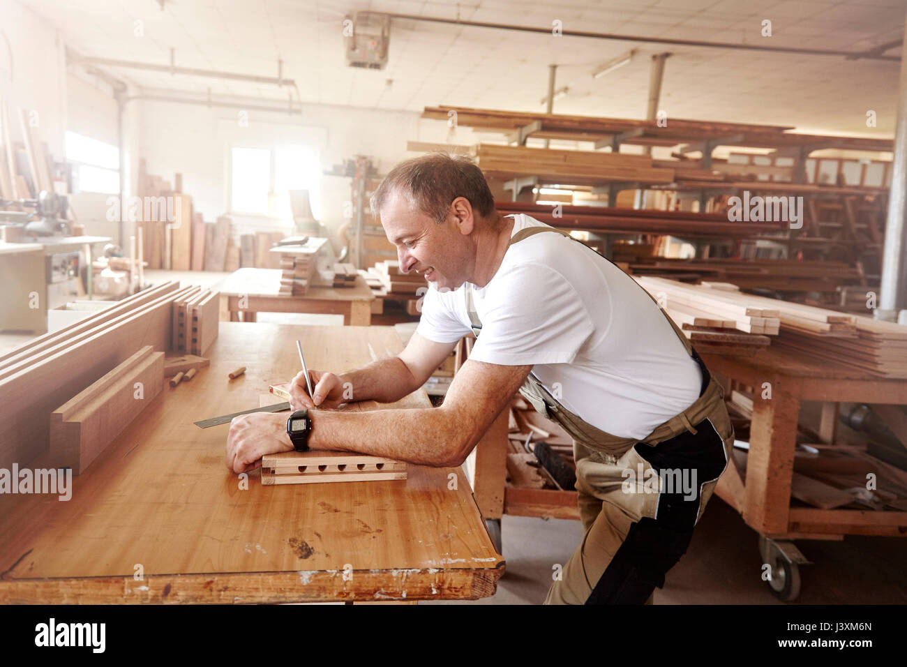 Male carpenter marking wood with pencil at workbench Stock Photo - Alamy