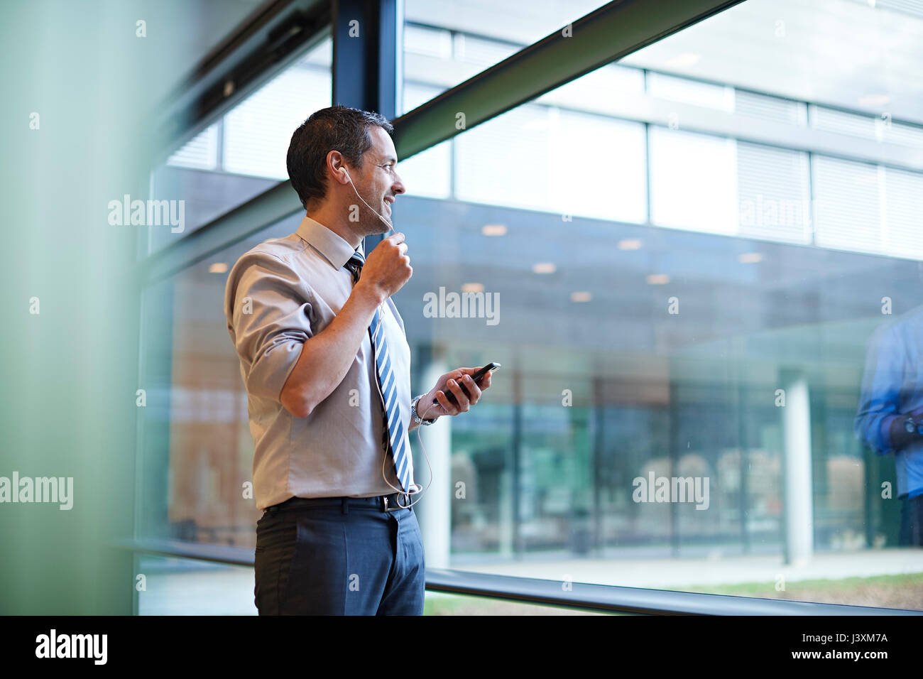 Mature businessman making telephone call while looking through office ...
