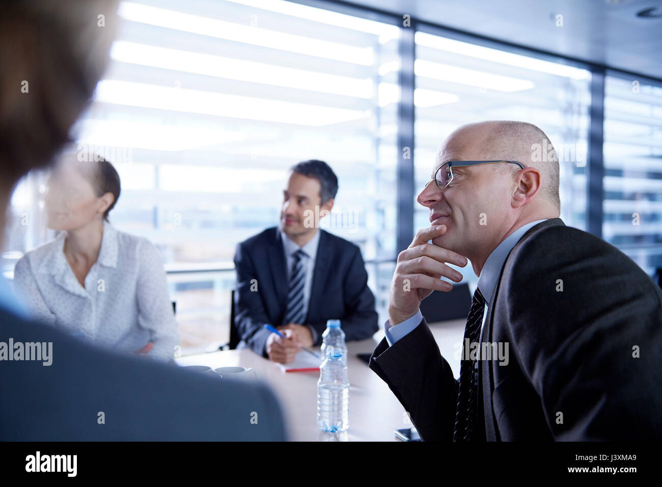 Over shoulder view of businesswoman and men listening at office meeting ...