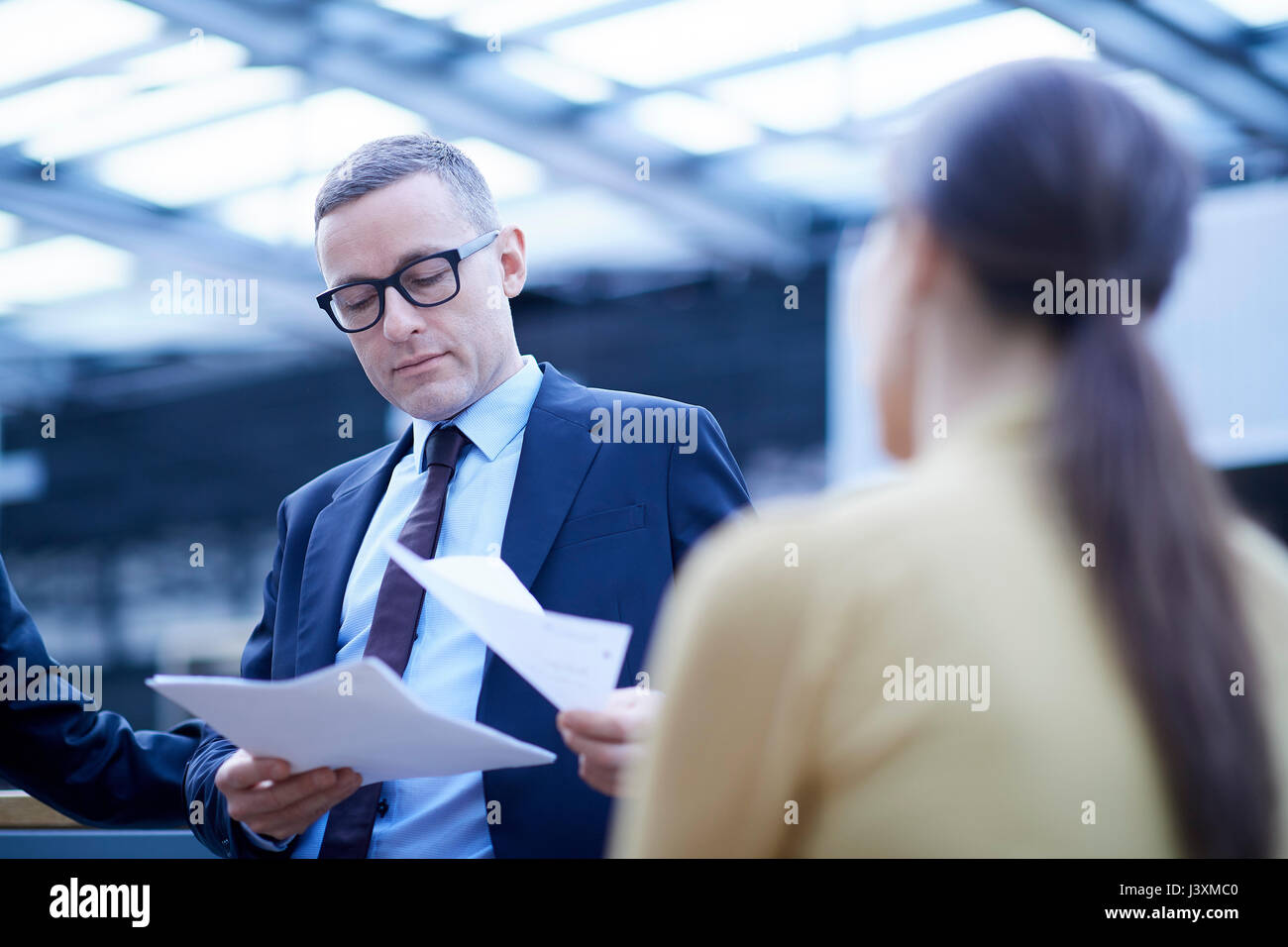 Businessman and woman reading paperwork in office Stock Photo - Alamy