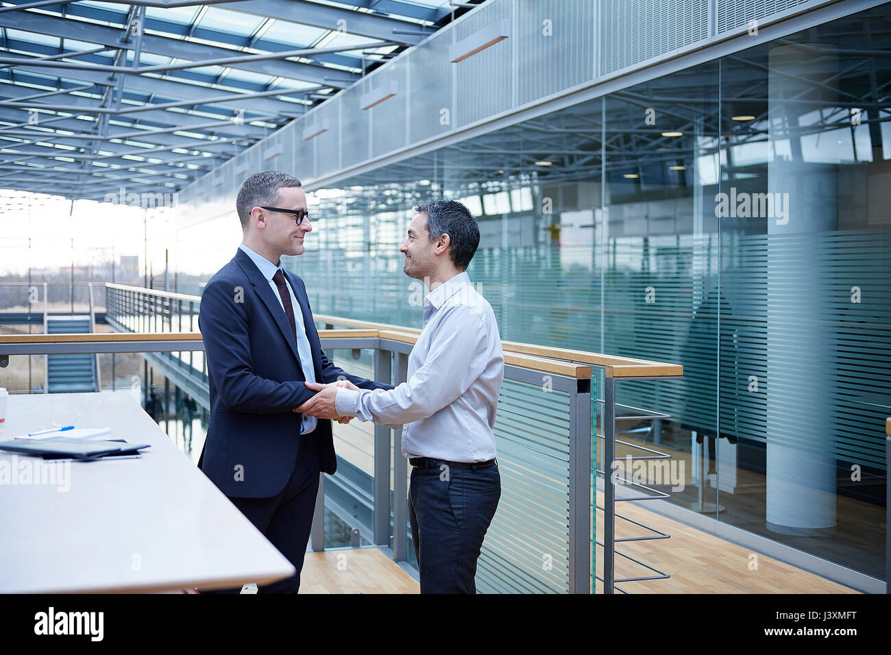 Two businessmen shaking hands on office balcony Stock Photo - Alamy