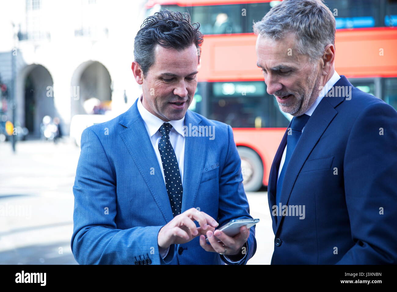 Businessmen in street looking at smartphone, London, UK Stock Photo - Alamy