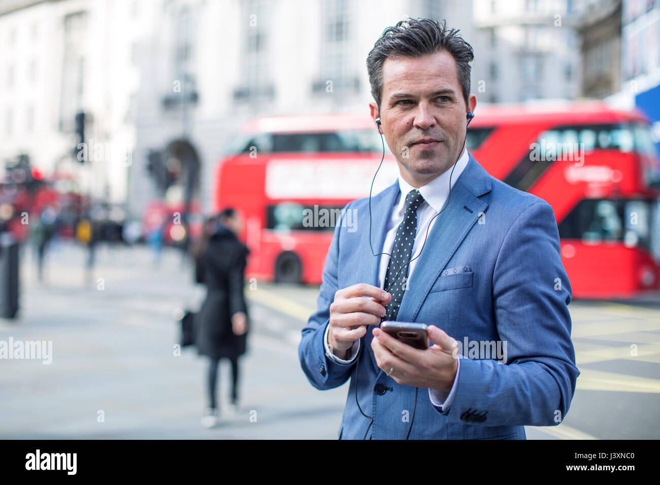 Businessmen in street with smartphone and earbuds, London, UK Stock ...