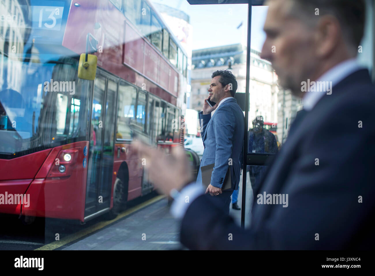 Businessman waiting at bus stop using smartphone, London, UK Stock ...
