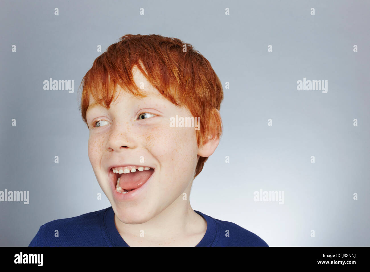Studio portrait of smiling red haired boy looking sideways Stock Photo ...