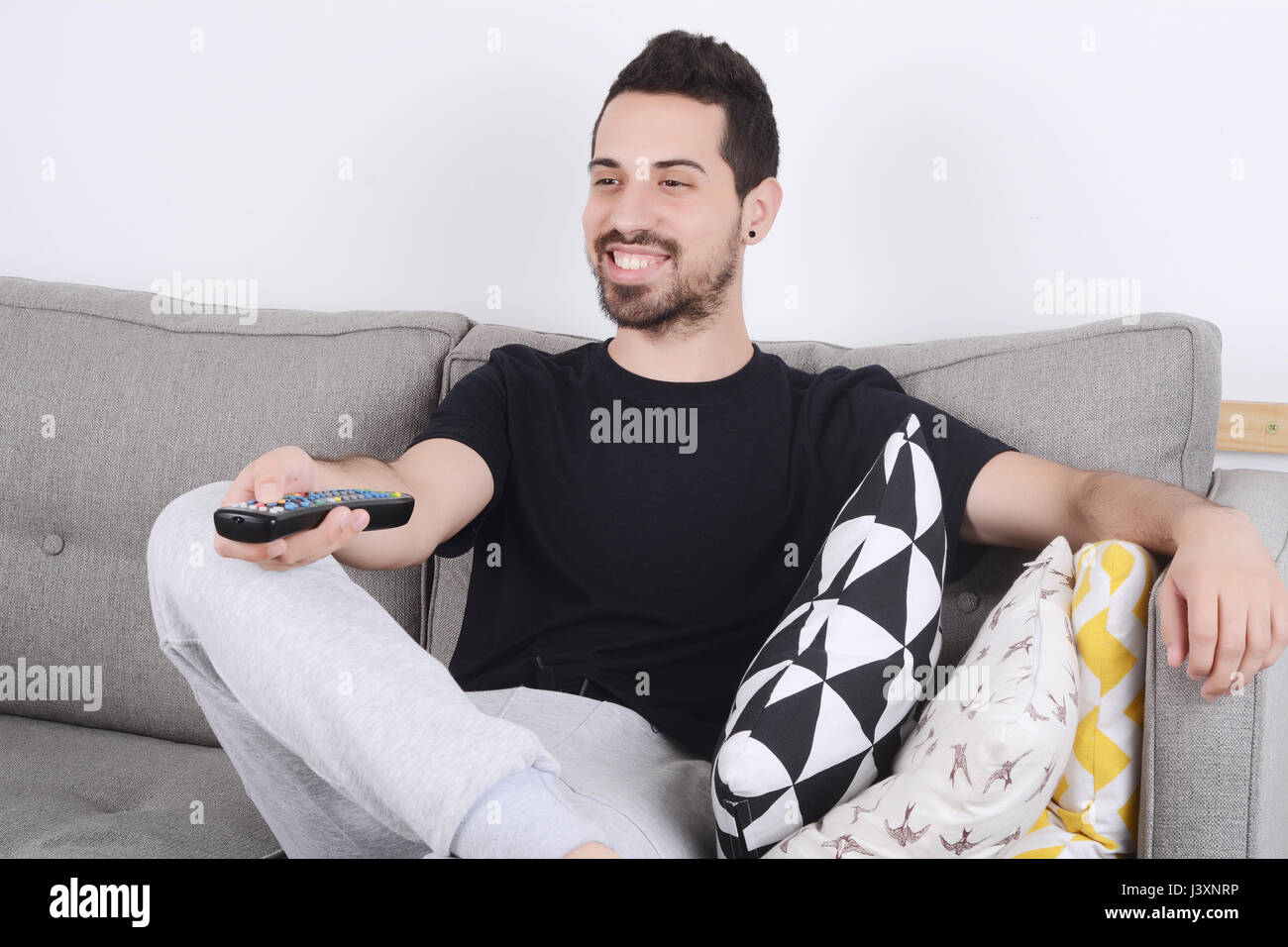 Attractive young man watching tv and relaxed on couch. Indoors Stock ...