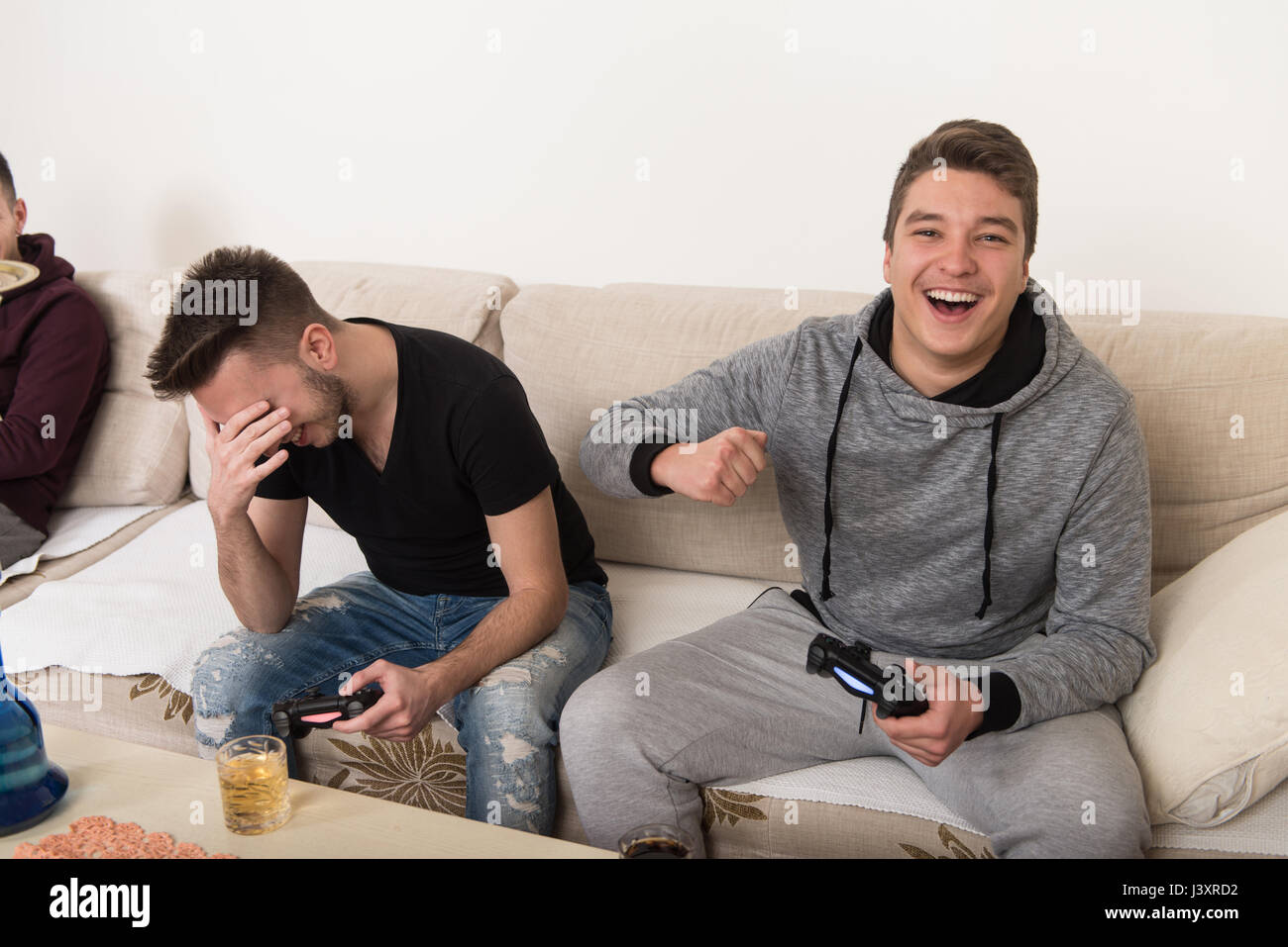 Three Young Brothers Having Happy Time Together Playing Video Games At ...