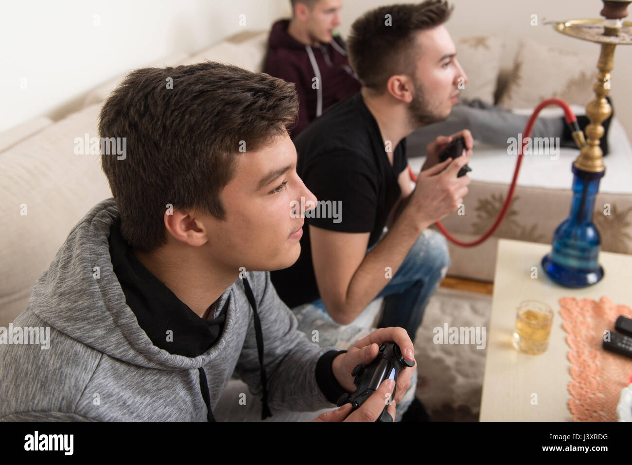 Three Young Brothers Having Happy Time Together Playing Video Games At ...