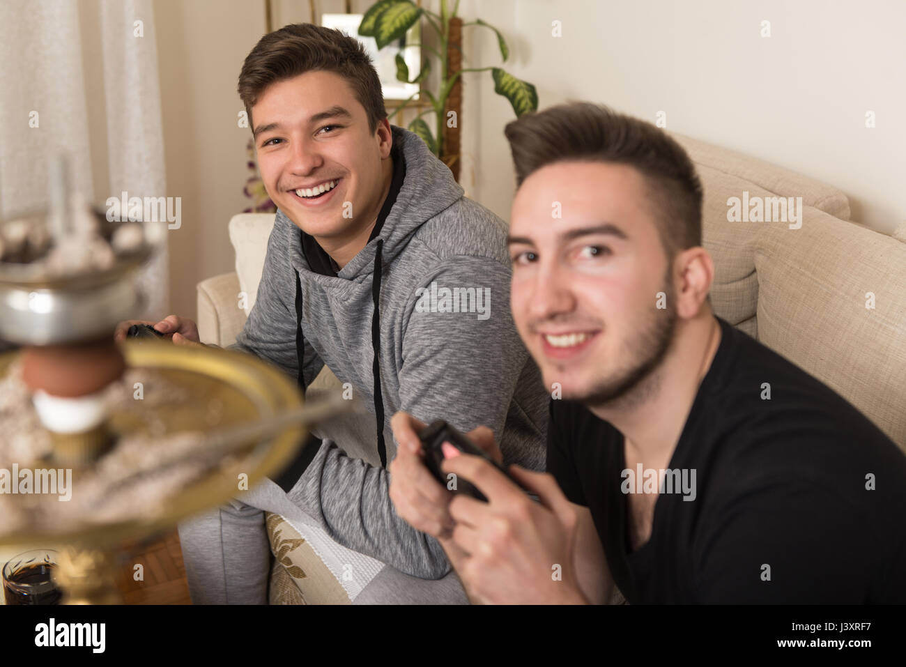 Two Brothers or Friends Playing Video Games Together as They Relax on a ...