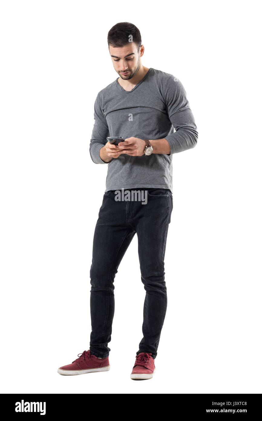 Stylish young trendy man typing message on cellphone. Full body length ...