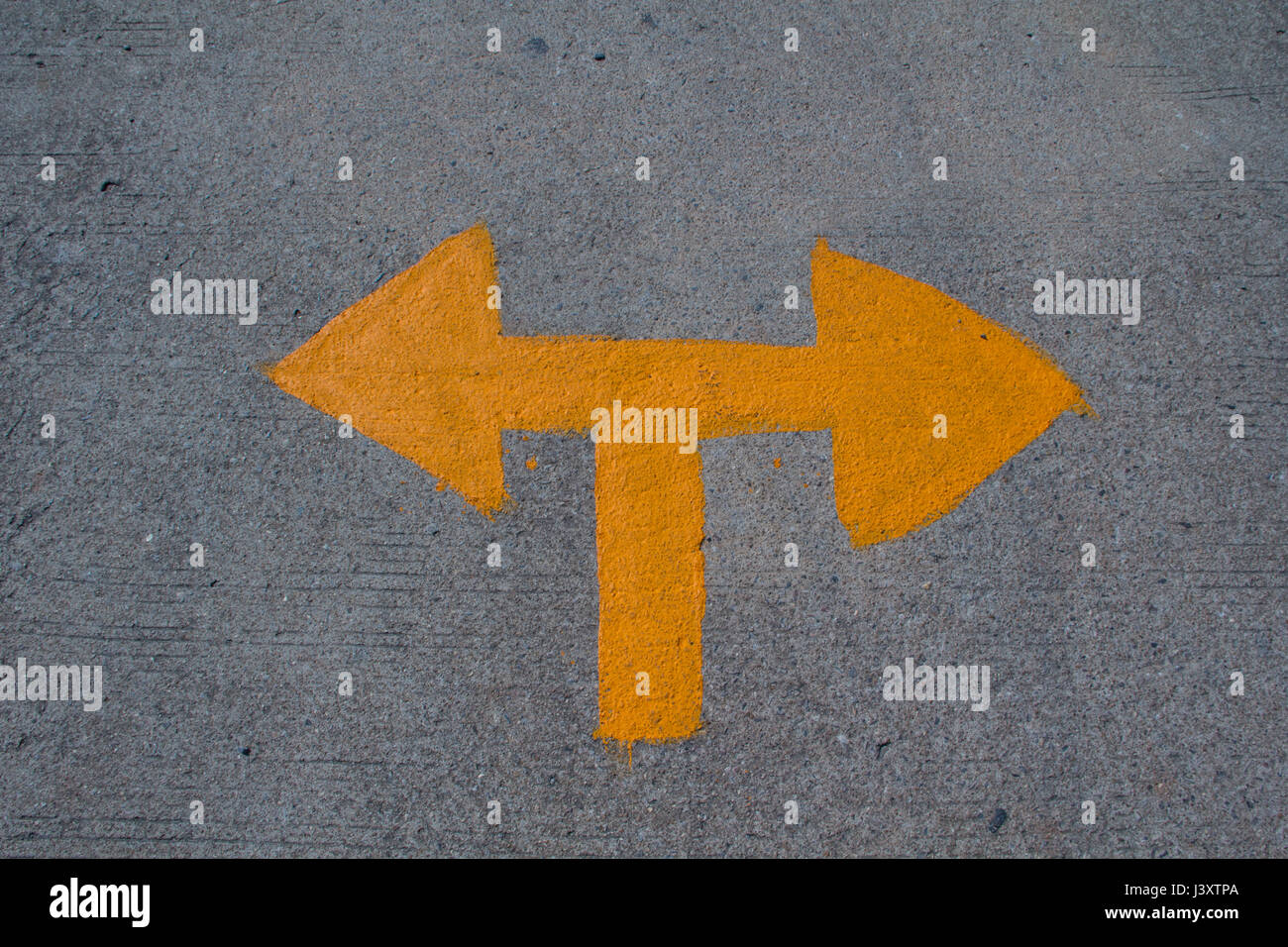 Hand drawn two way orange arrow on the asphalt surface. Making decision ...