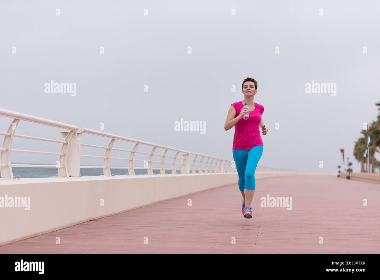 very active young beautiful woman busy running on the promenade along ...