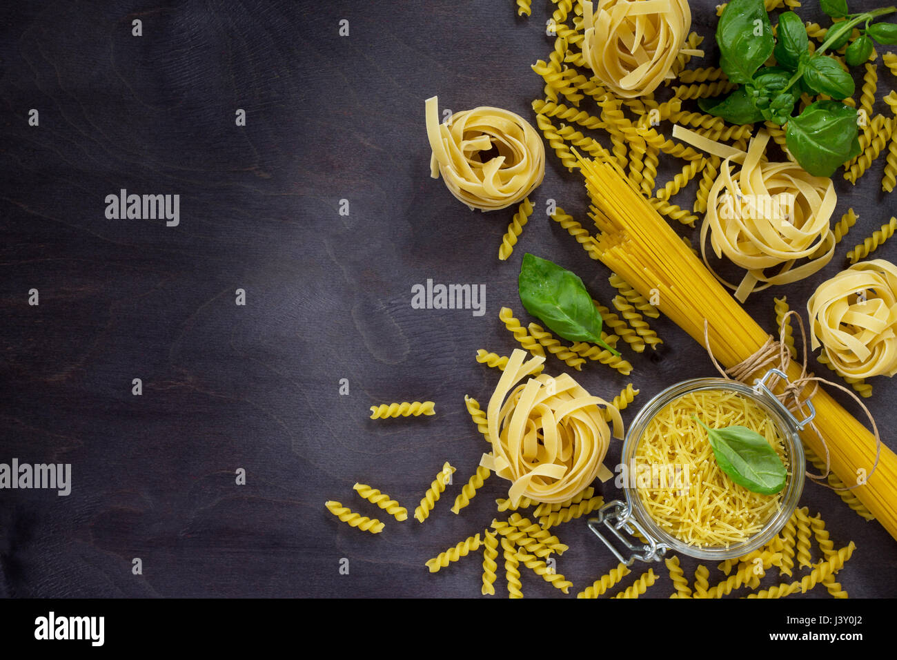 Different types of pasta with basil on the kitchen wooden table Stock ...