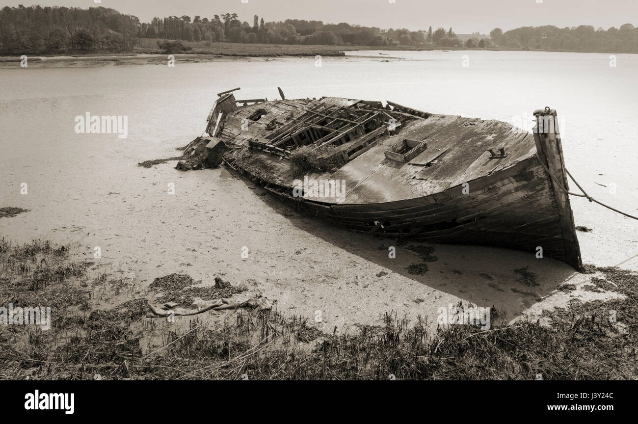 Derelict and rotting wooden boat have submerged in silt at low tide on ...