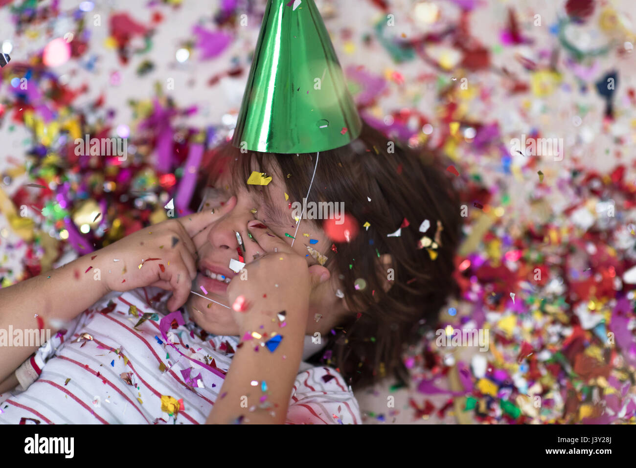 Happy kid celebrating party with blowing confetti while lying on the ...