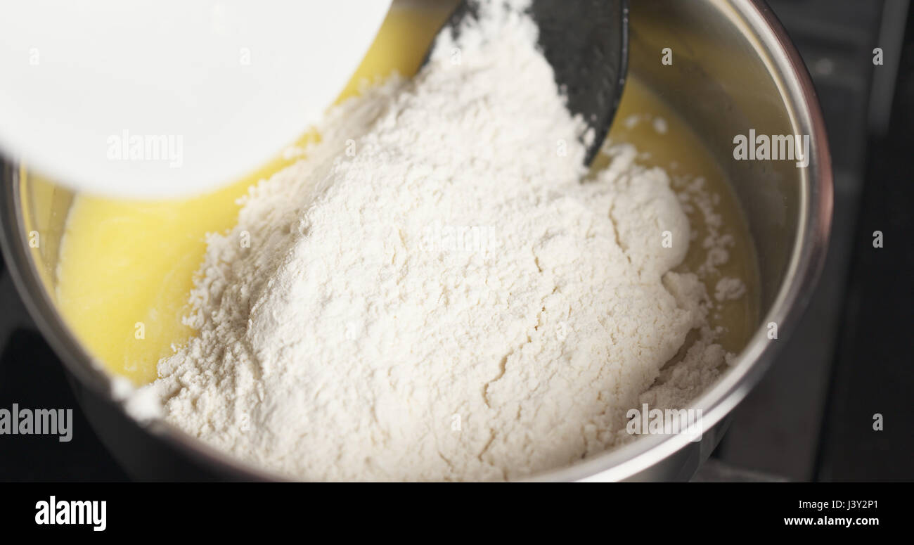 Handheld shot of mixing flour with butter mix for making choux dough ...
