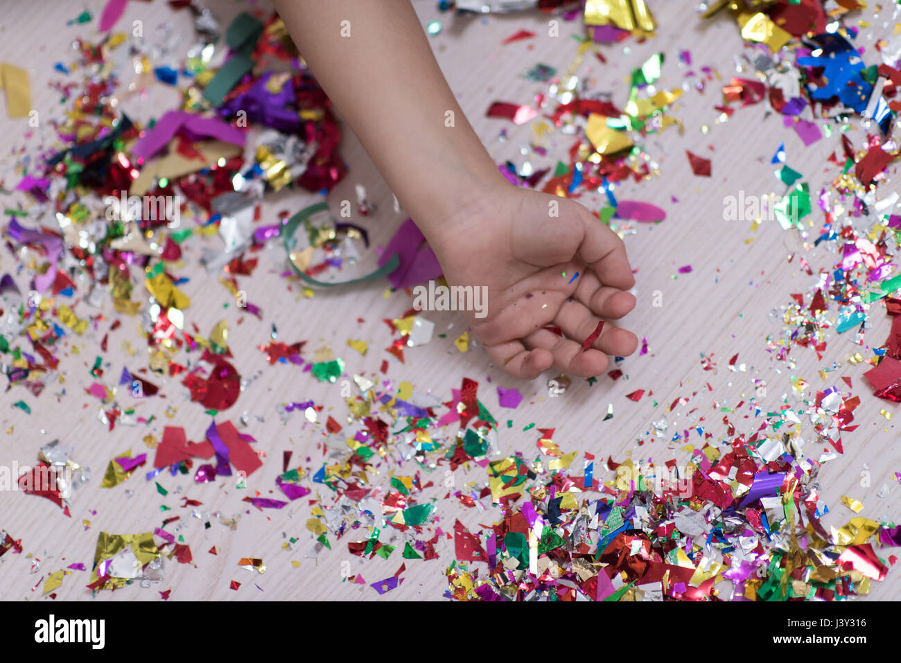 children's hand with confetti on the wooden floor in the background ...