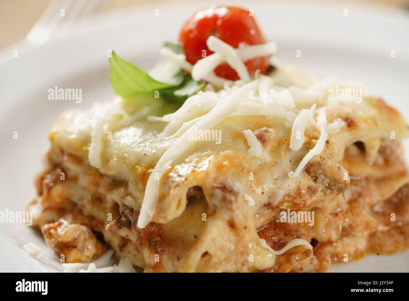 homemade lasagna portion on white plate on wood table Stock Photo - Alamy