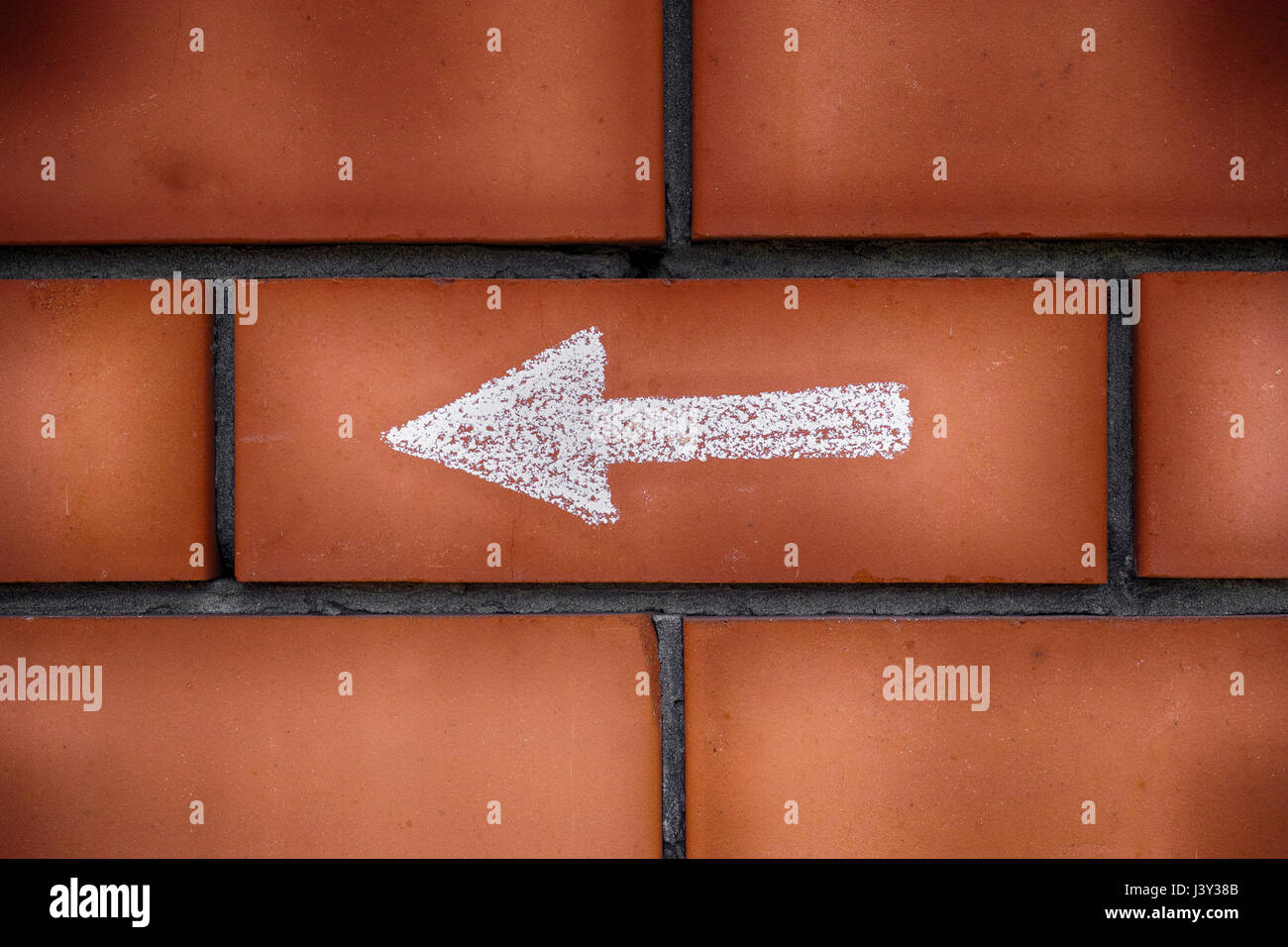 Arrow pointing left drawn on bricks. Close up Stock Photo - Alamy