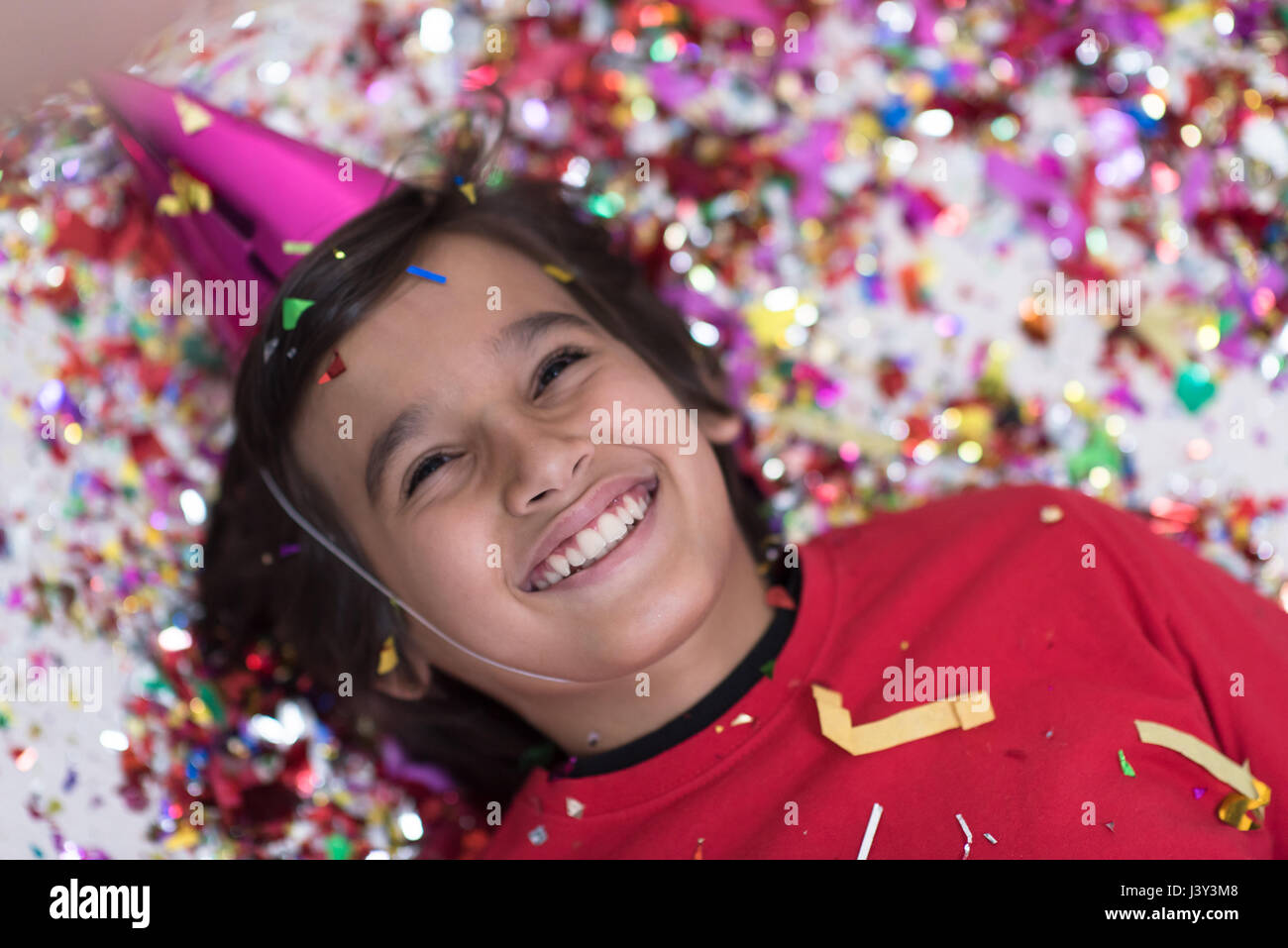 Happy kid celebrating party with blowing confetti while lying on the ...
