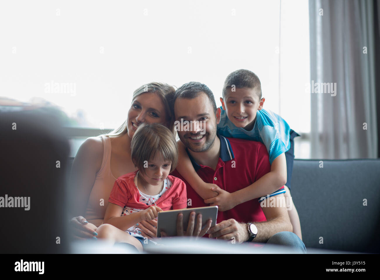 Happy Young Family Playing Together with tablet at home sitting on the ...