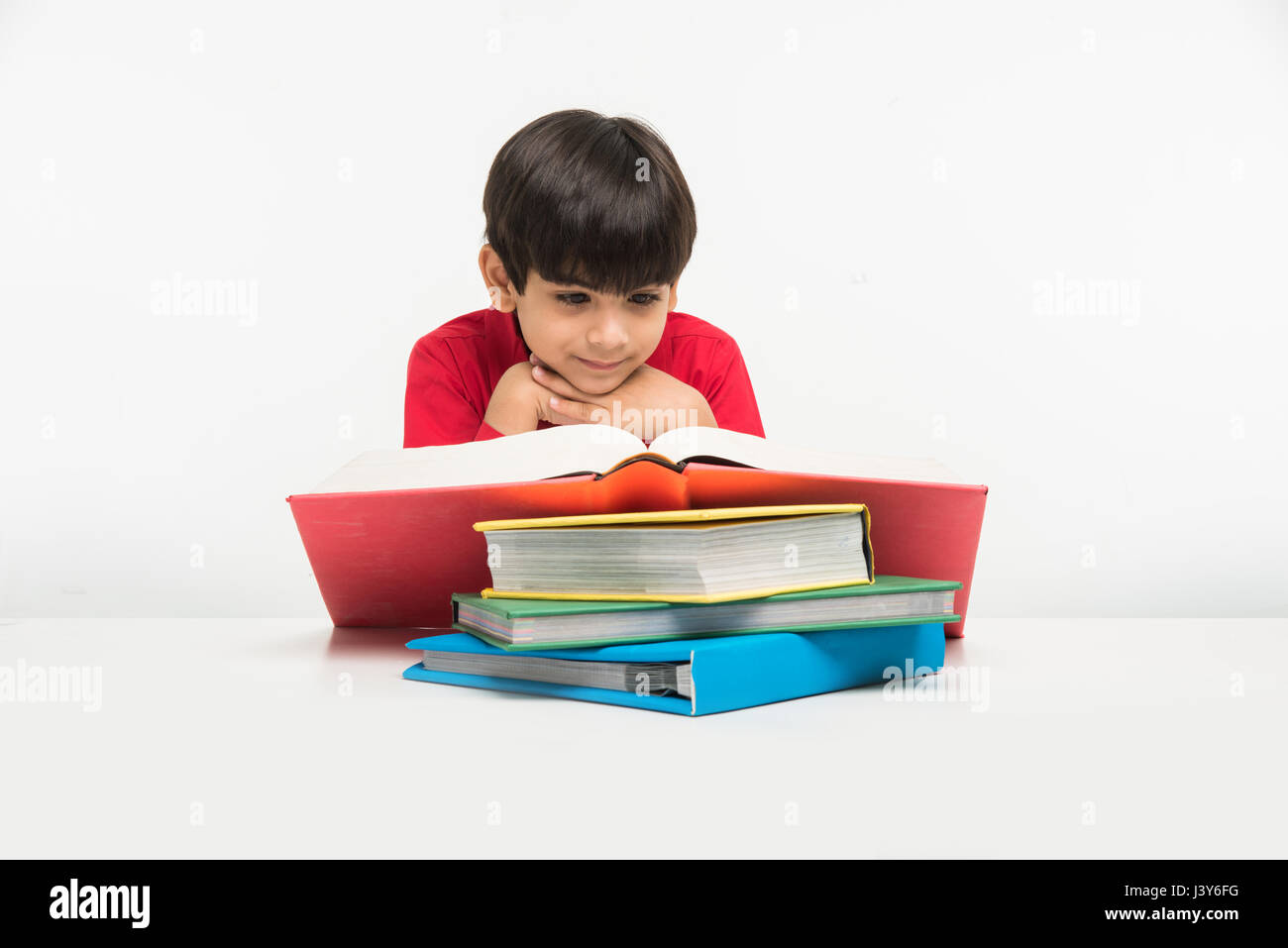 Cute little Indian/Asian boy reading book over study table, isolated ...