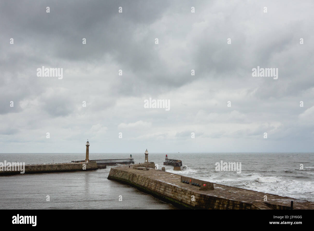 whitby harbour on a rainy day, with moody sky, waves lapping against ...