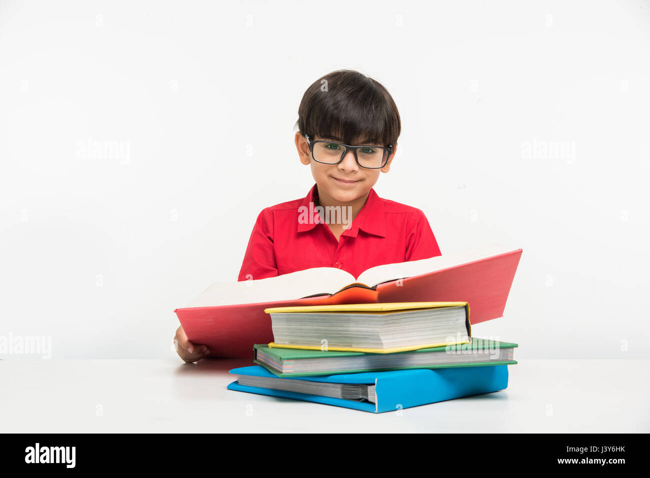 Cute little Indian/Asian boy reading book over study table, isolated ...