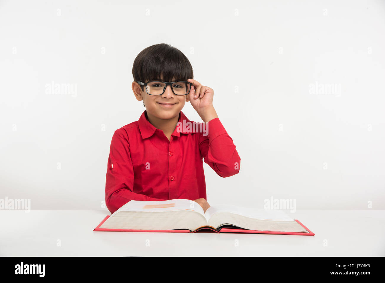 Cute little Indian/Asian boy reading book over study table, isolated ...
